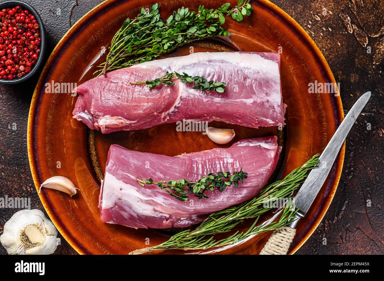 Fresh pork tenderloin meat with rosemary and thyme. Dark background ...