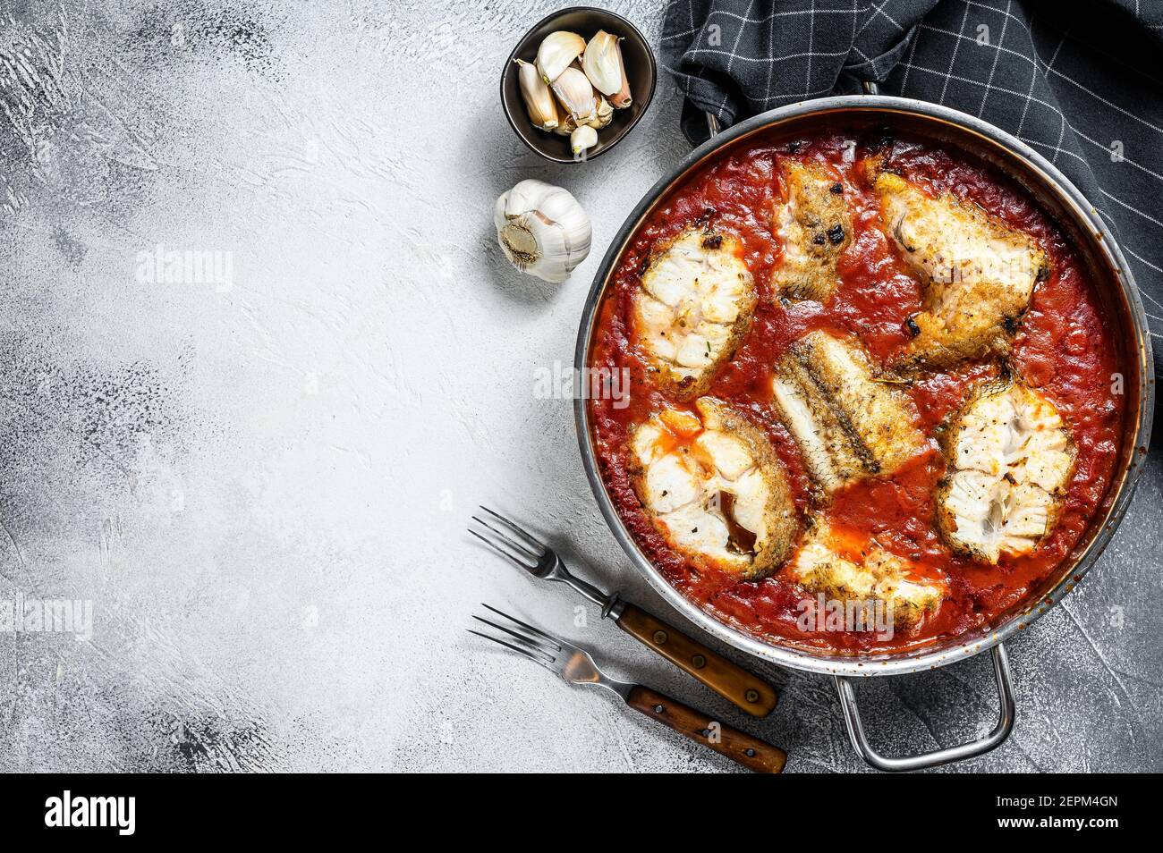 Baked grenadier macrurus white fish with tomato in a pan. White Wooden ...