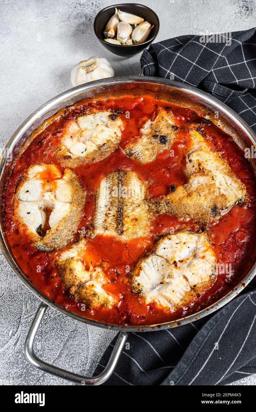 Baked grenadier macrurus white fish with tomato in a pan. White Wooden ...