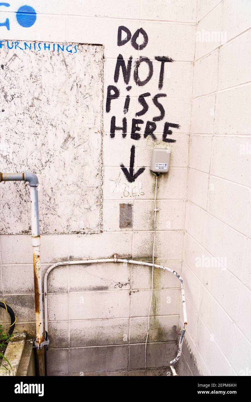 A sign painted on the wall of a building in an urban area telling ...