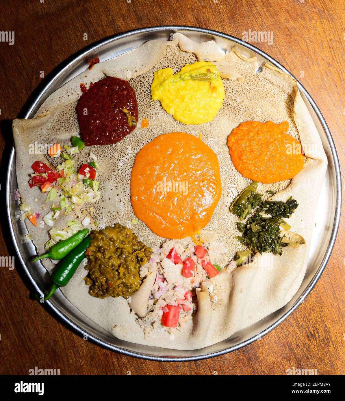 Ethiopians enjoying a traditional Injera dish with variety of veggies ...