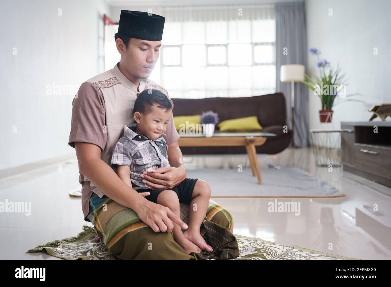 portrait of a muslim father praying at home while babysit his son Stock ...