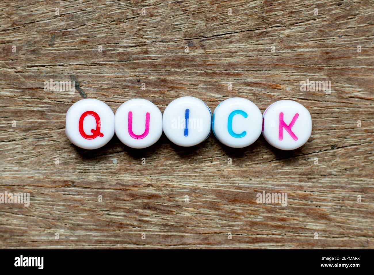 White bead with color letter in word quick on wood background Stock ...