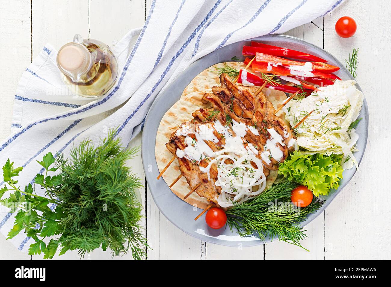 Grilled chicken kebab with pita, fresh vegetables on a white table ...