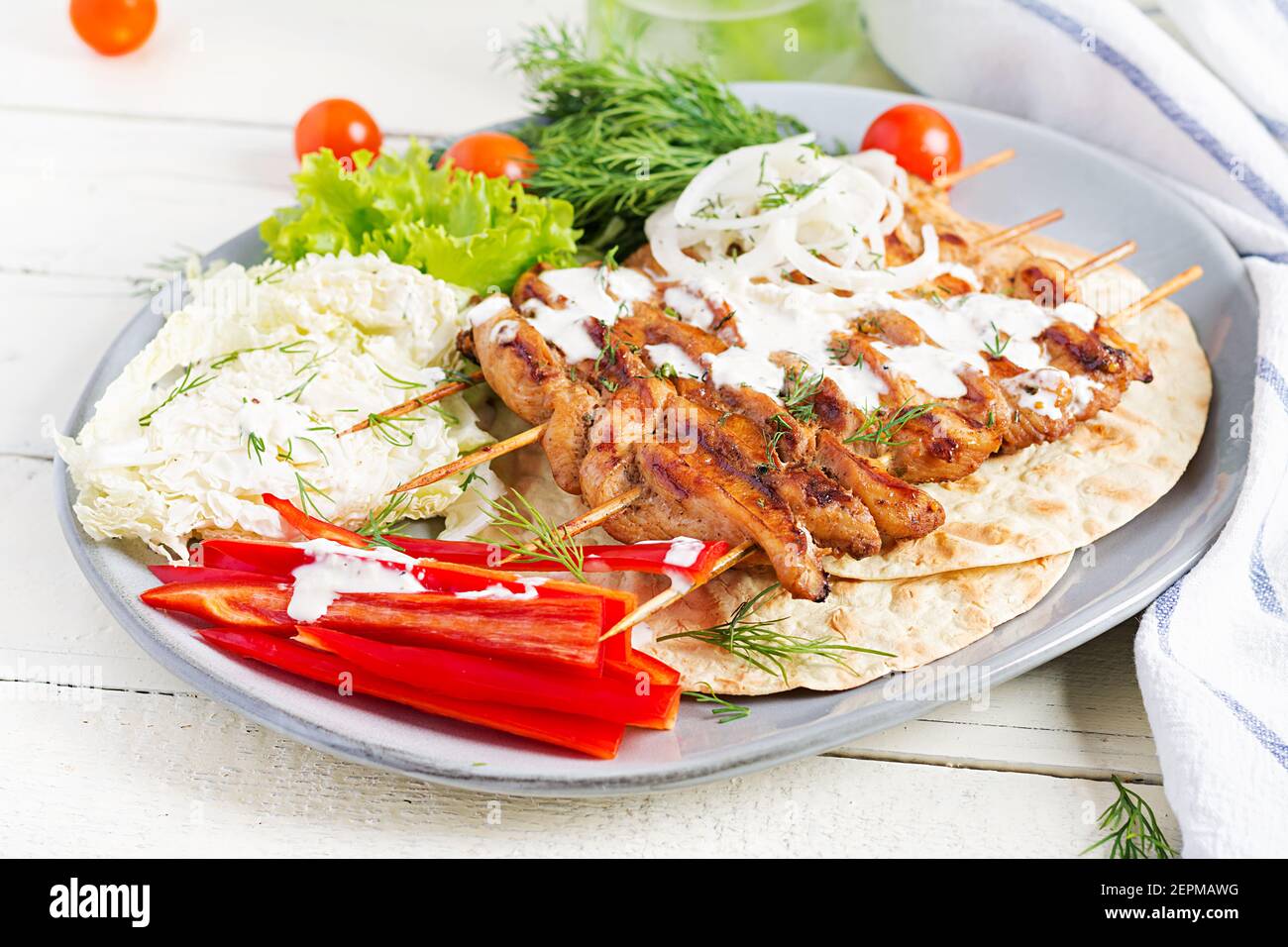 Grilled chicken kebab with pita, fresh vegetables on a white table ...
