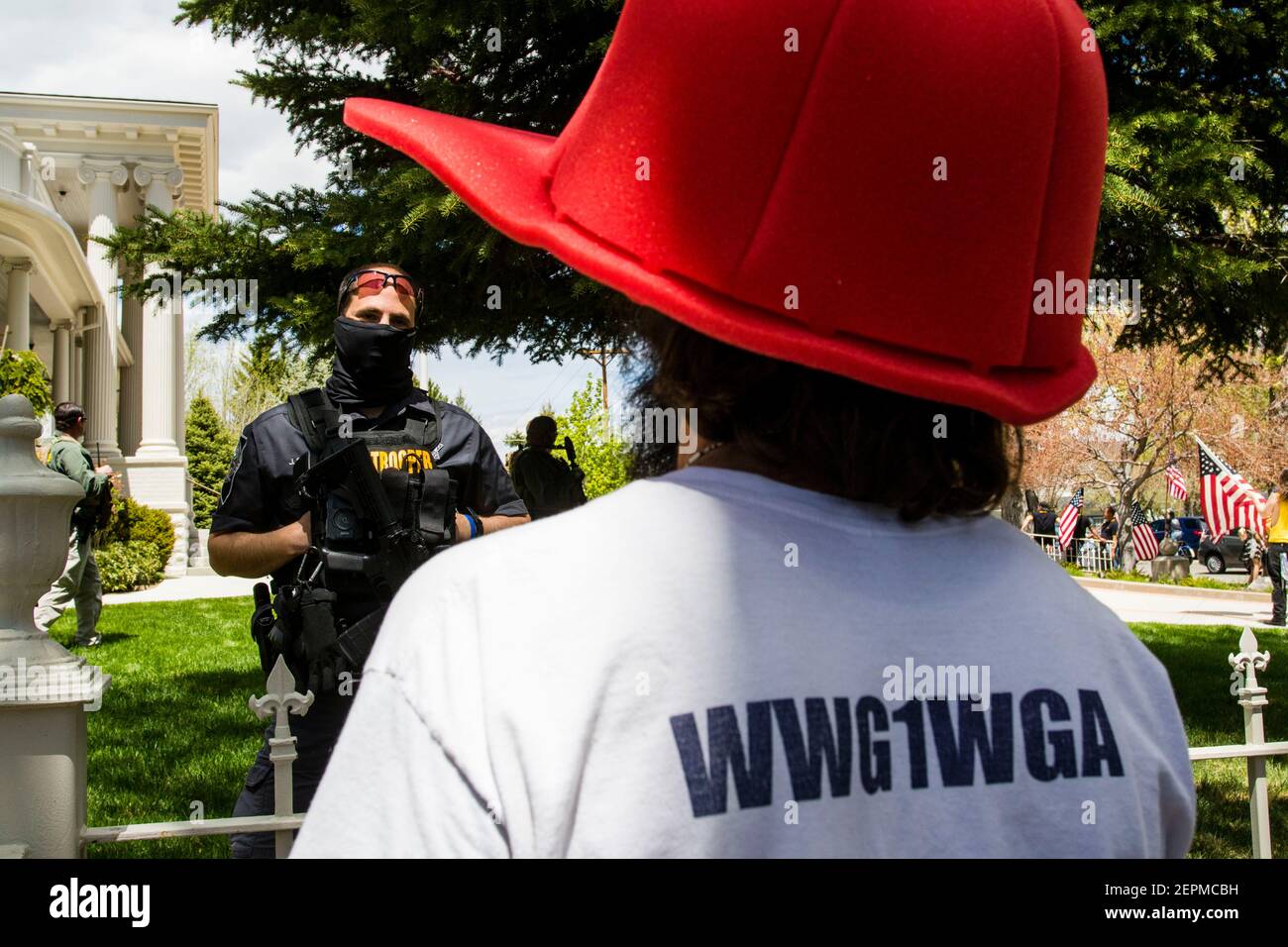 A man wearing a foam trump hat and a Qanon shirt yelling at a police ...