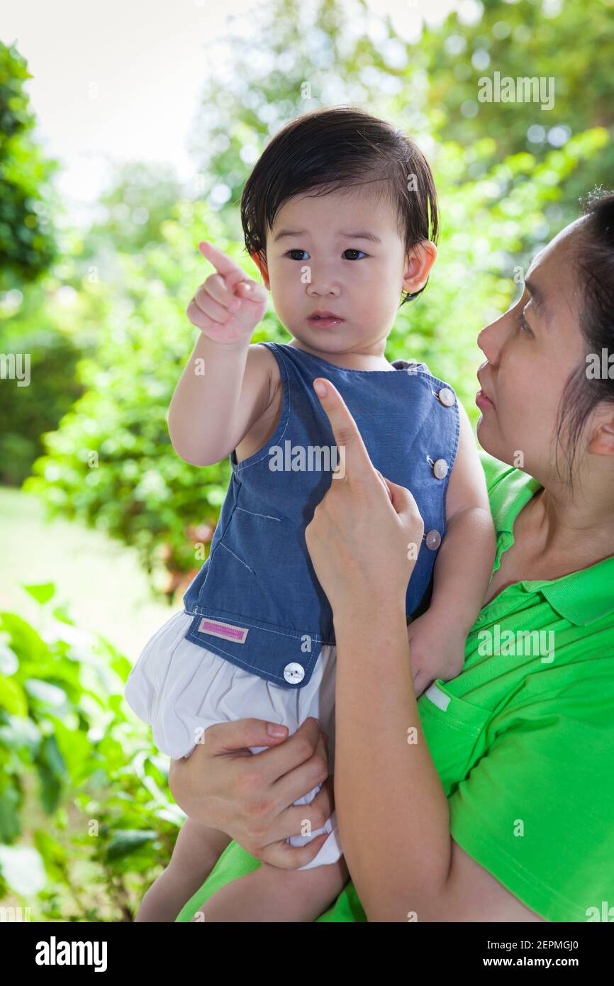 Young asian woman and cute daughter talking together in the backyard ...