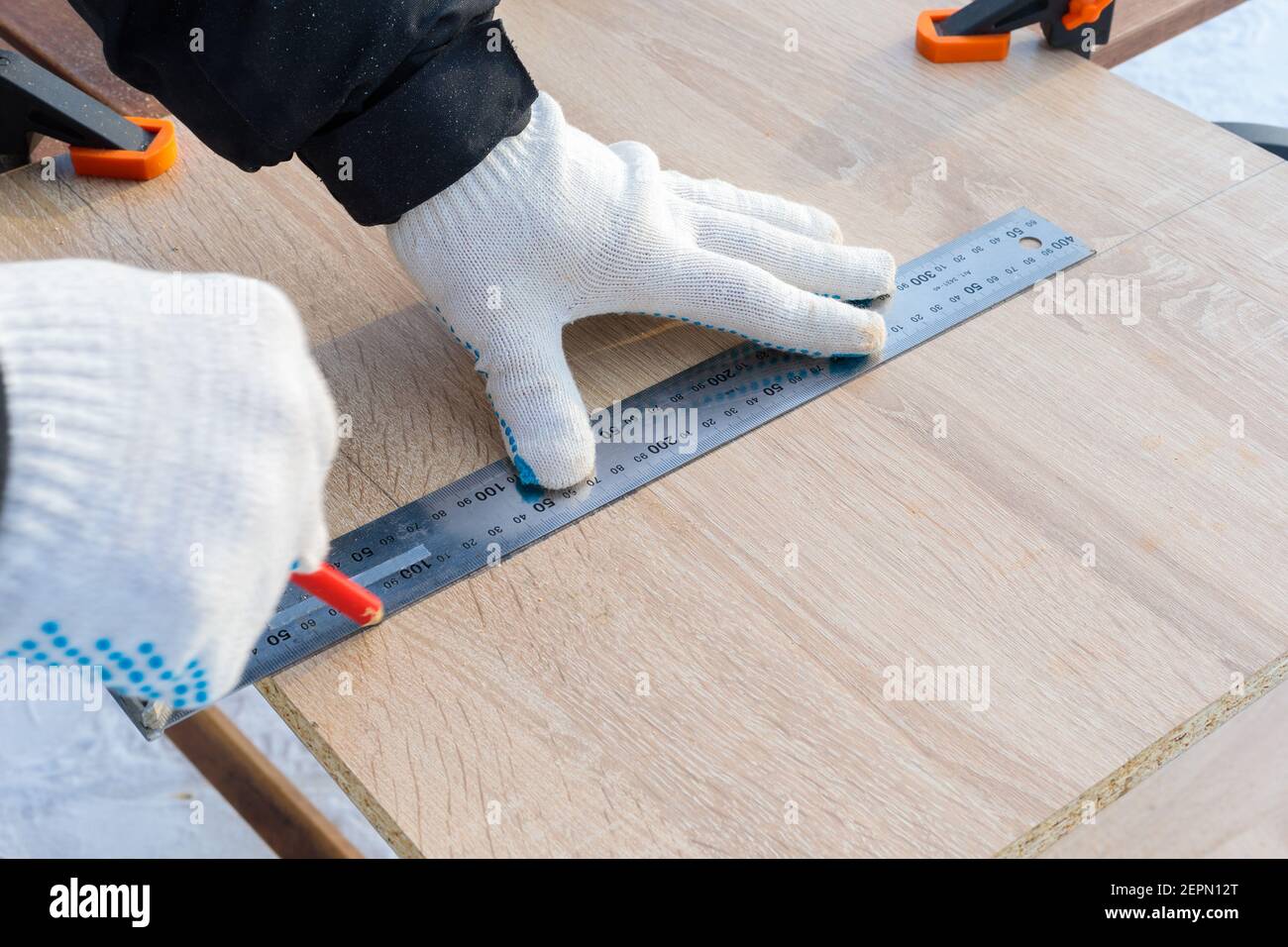 A man, a worker, marks it with a square and a pencil on a chipboard ...