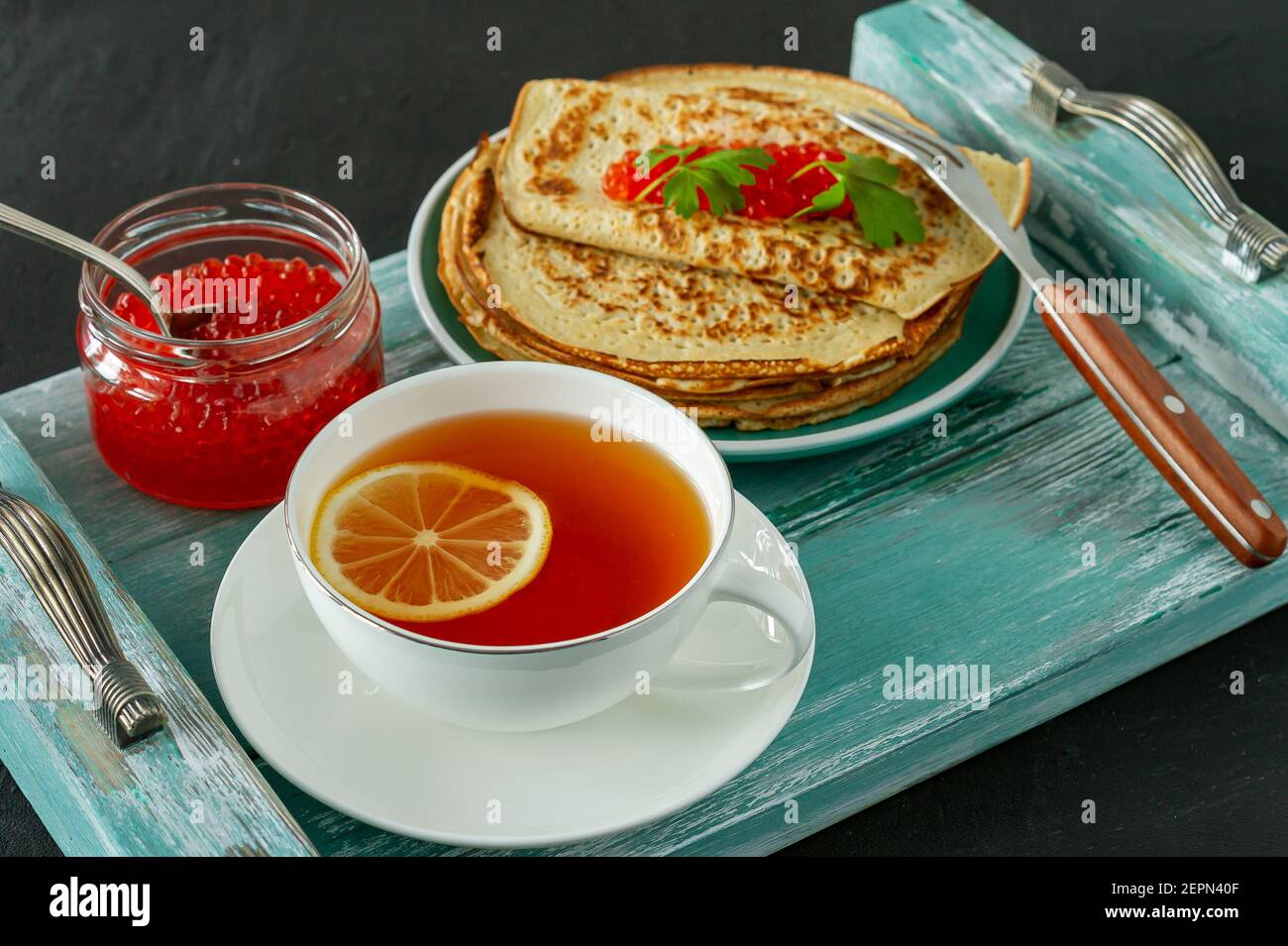 Traditional Russian Crepes Blini stacked in a plate with red caviar and ...