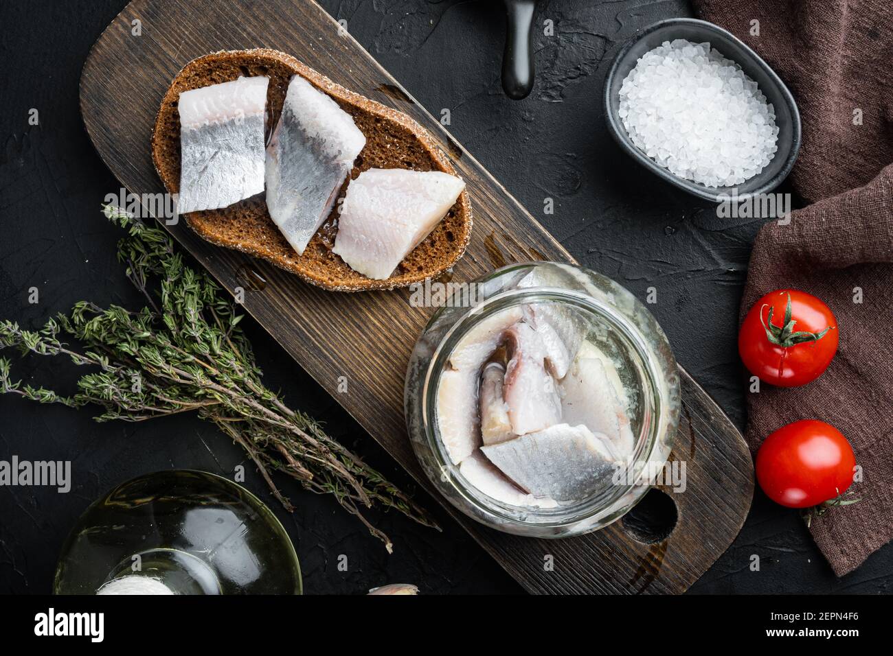 Canned Wild Herring Fillets set, on wooden cutting board, on black ...