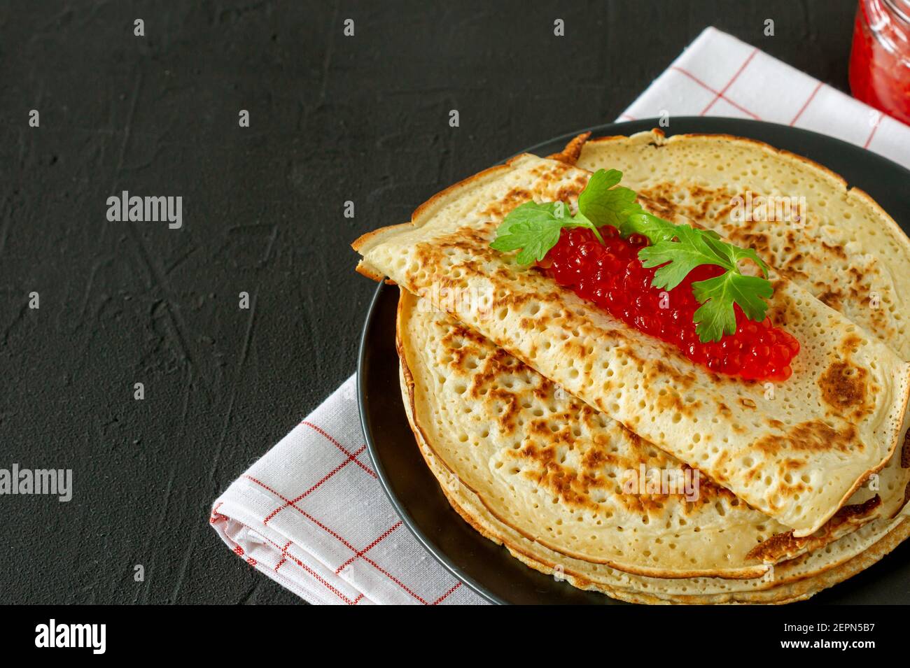 Traditional Russian Crepes Blini stacked in a plate with red caviar on ...