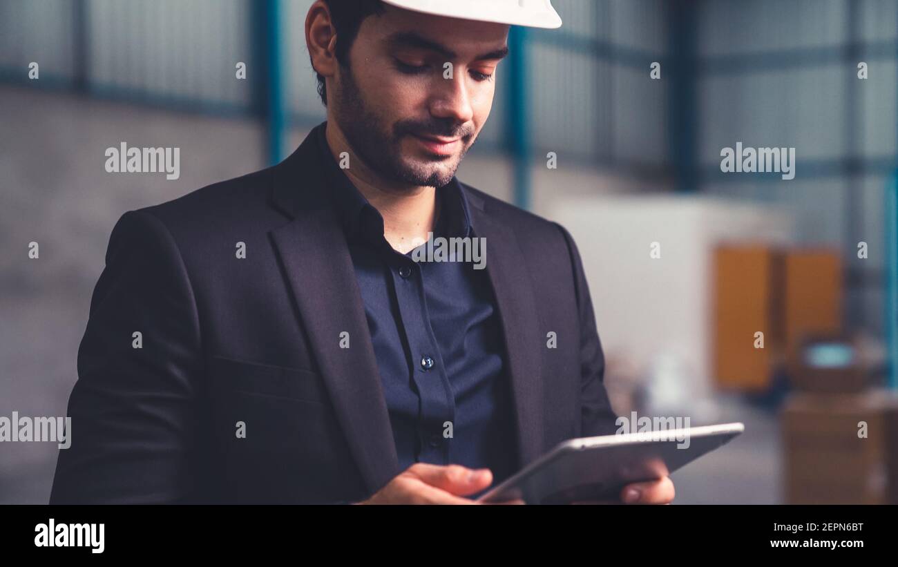 Factory manager using tablet computer in warehouse or factory ...