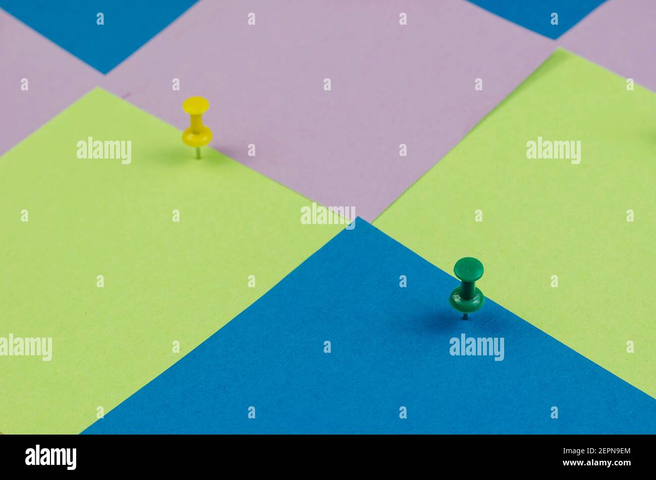 Two pushpins and many colorful sticky notes. Green and yellow pushpins ...