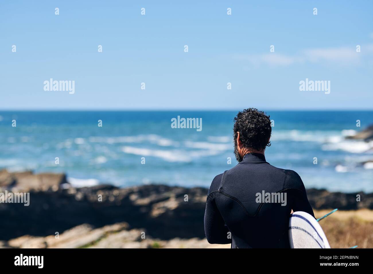 Back view full length of anonymous man wearing surfing suit standing ...