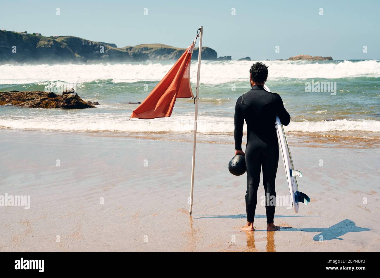 Back view full length of anonymous man wearing surfing suit standing ...