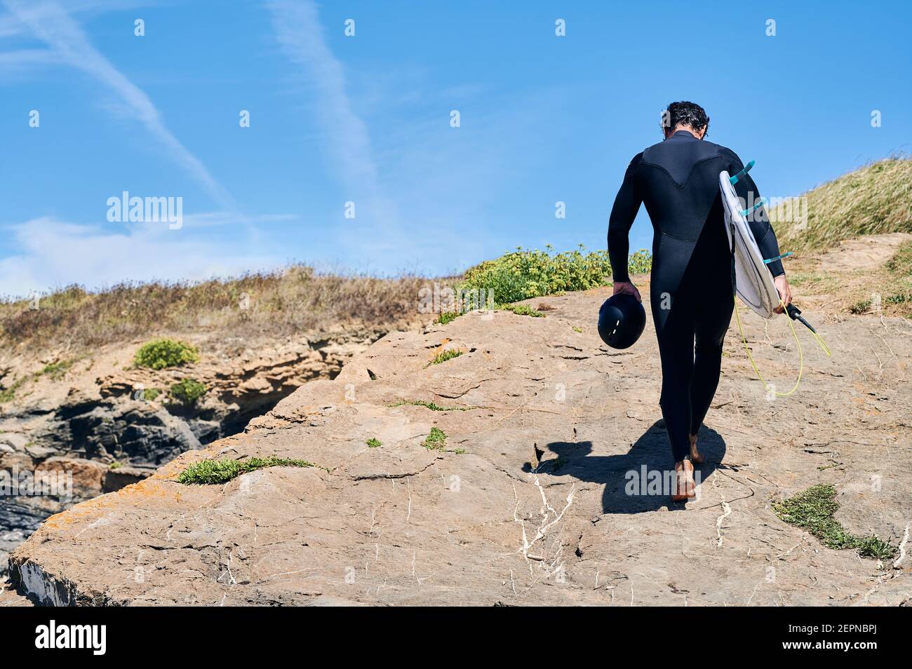 Back view full length of anonymous man wearing surfing suit standing ...