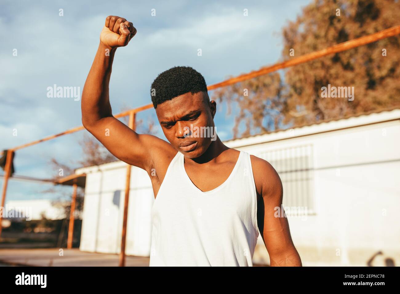 Masculine ethnic male protester in undershirt standing with raised arm ...