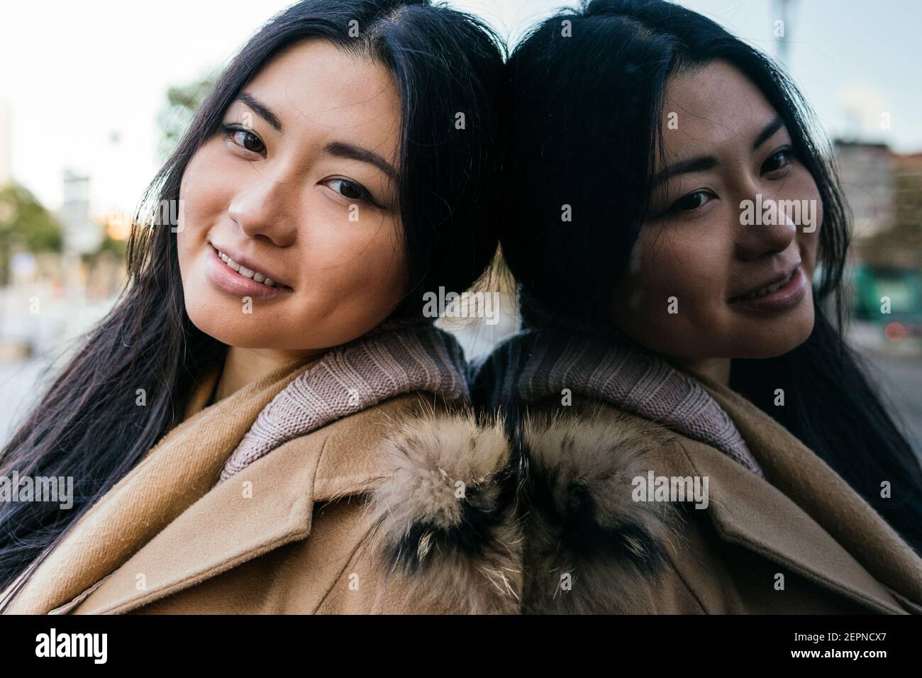 Happy Asian Woman with long hair reflecting in glass surface of ...