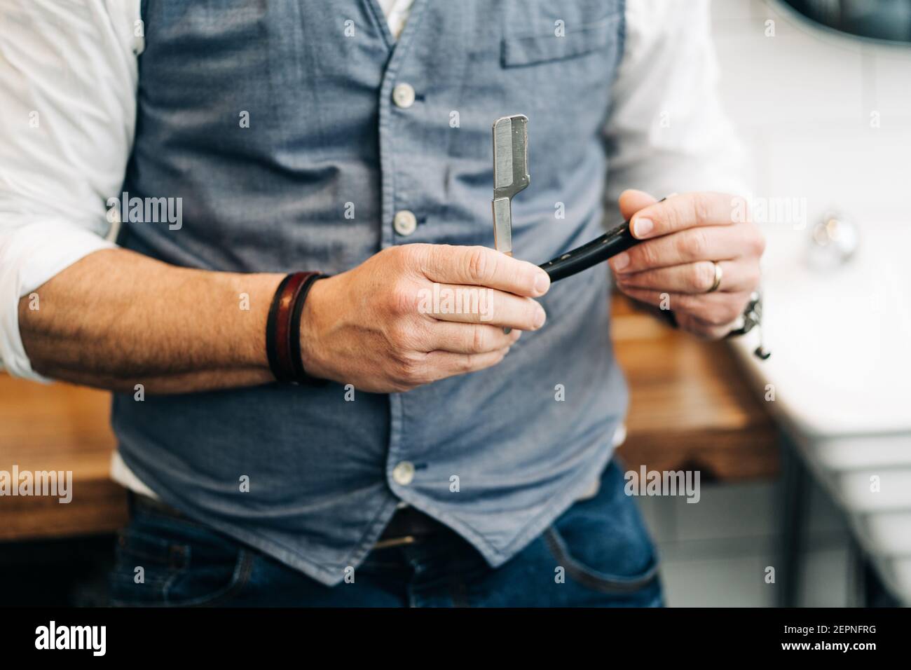 Crop unrecognizable male stylist holding straight razor with sharp ...