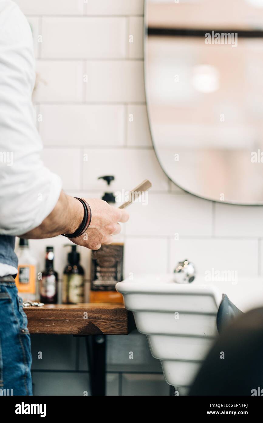 Crop unrecognizable male stylist holding straight razor with sharp ...