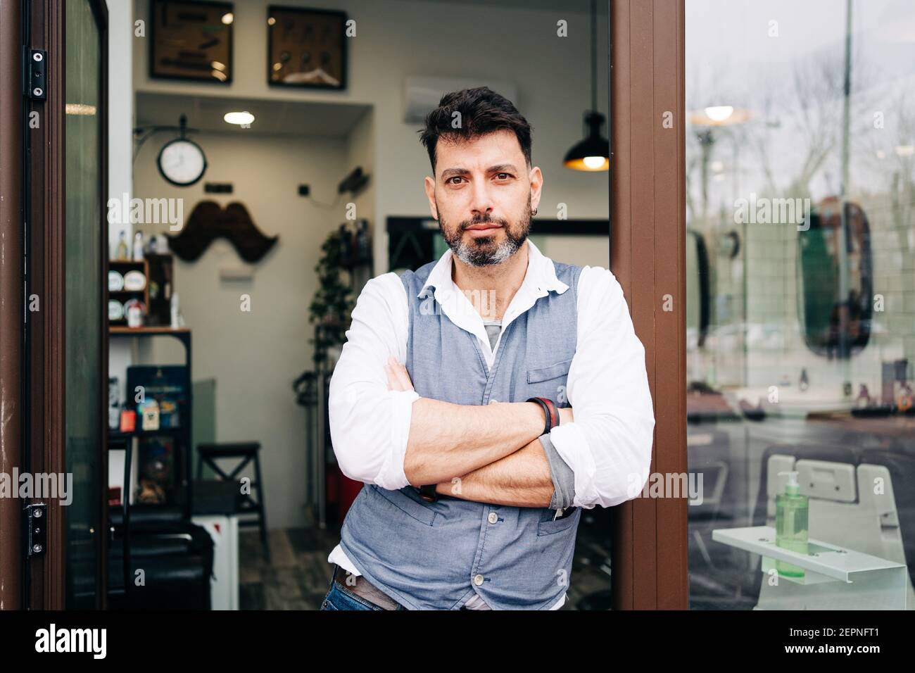 Adult bearded male beauty master with arms crossed looking at camera ...