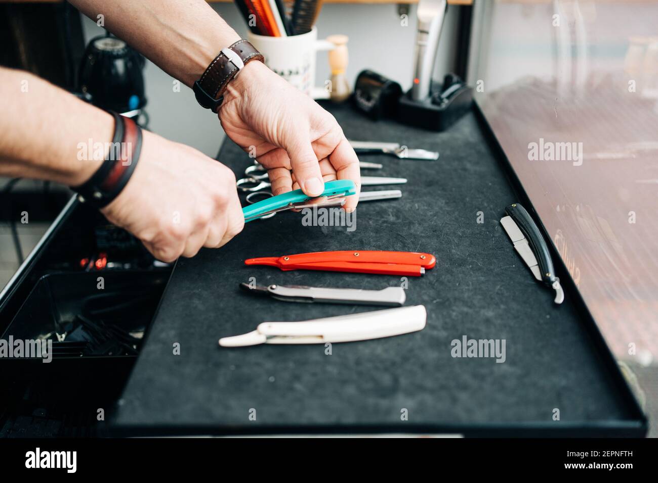 Crop anonymous beauty master with collection of razors and manual ...