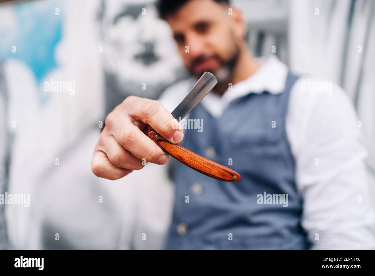Crop masculine male stylist demonstrating straight razor with sharp ...
