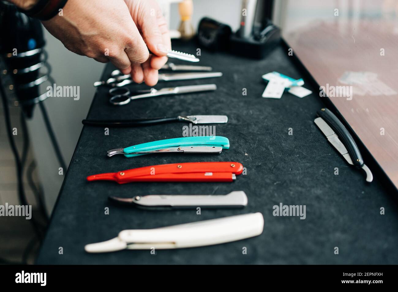 Crop anonymous beauty master with collection of razors and manual ...