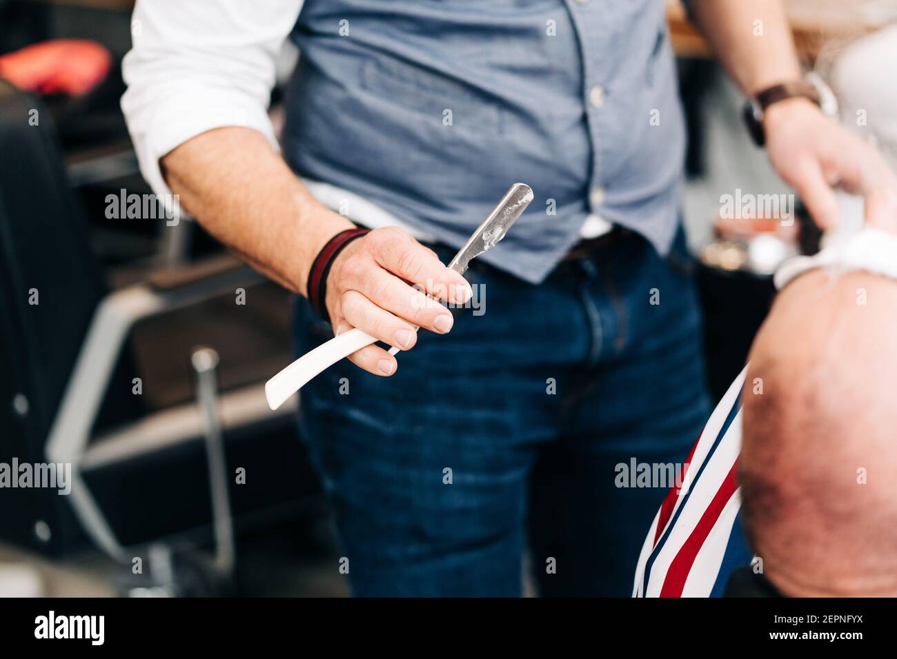 Crop unrecognizable male stylist holding straight razor with sharp ...