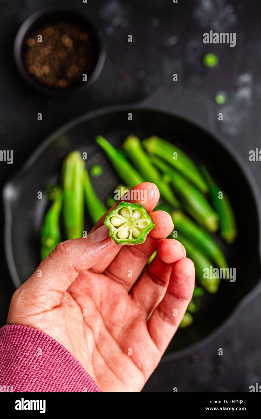 From above crop unrecognizable person holding ripe okra over table with ...