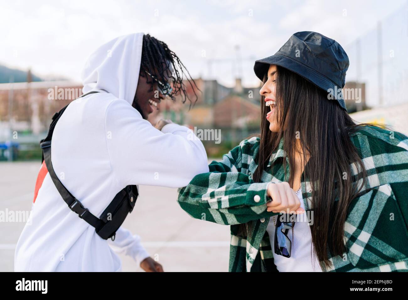 Young happy multiracial partners in trendy wear greeting each other ...