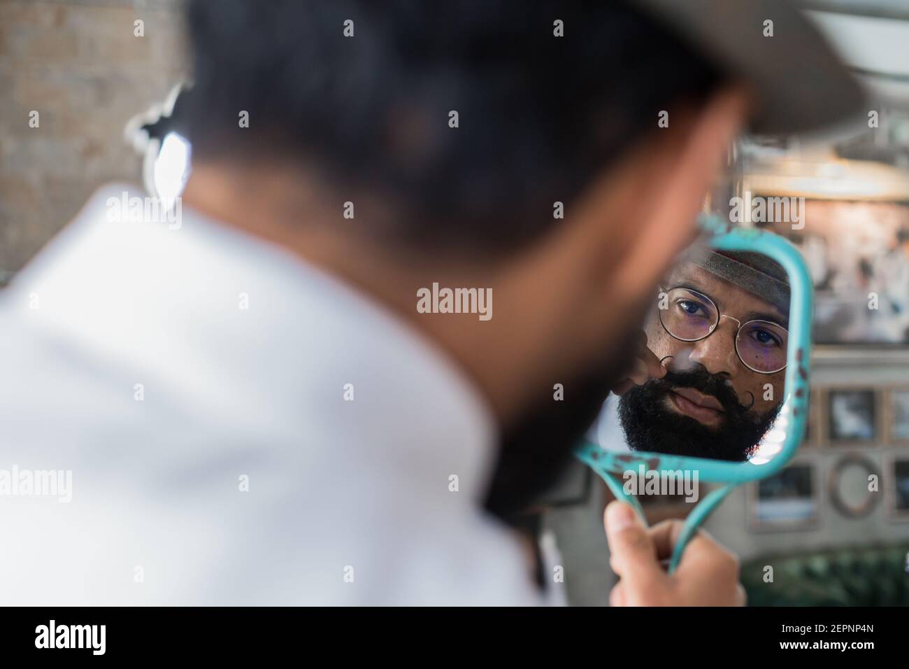 Back view of crop bearded dandy ethnic male hairdresser in eyeglasses ...