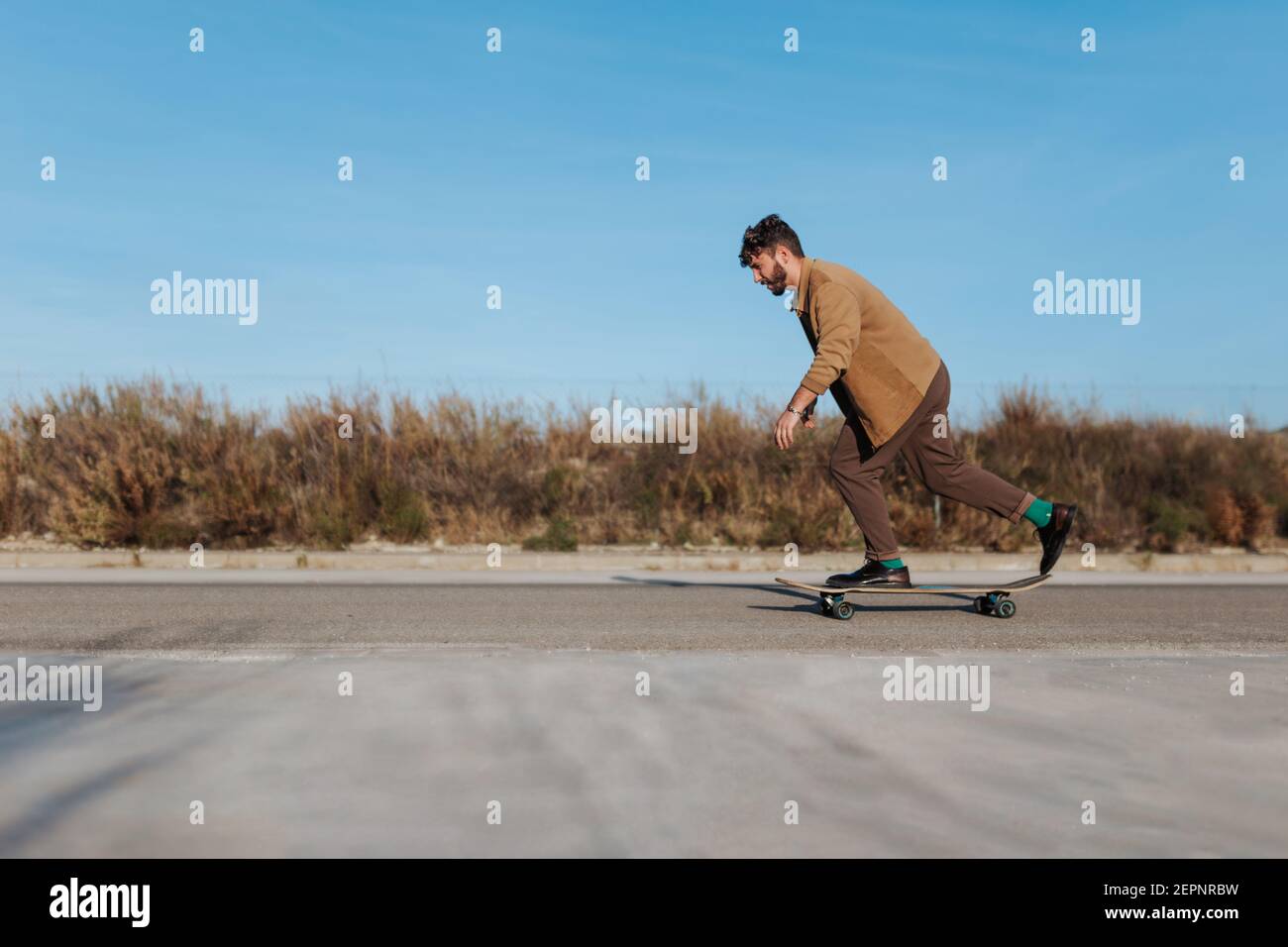 Side view full body young bearded male skater in stylish wear riding ...