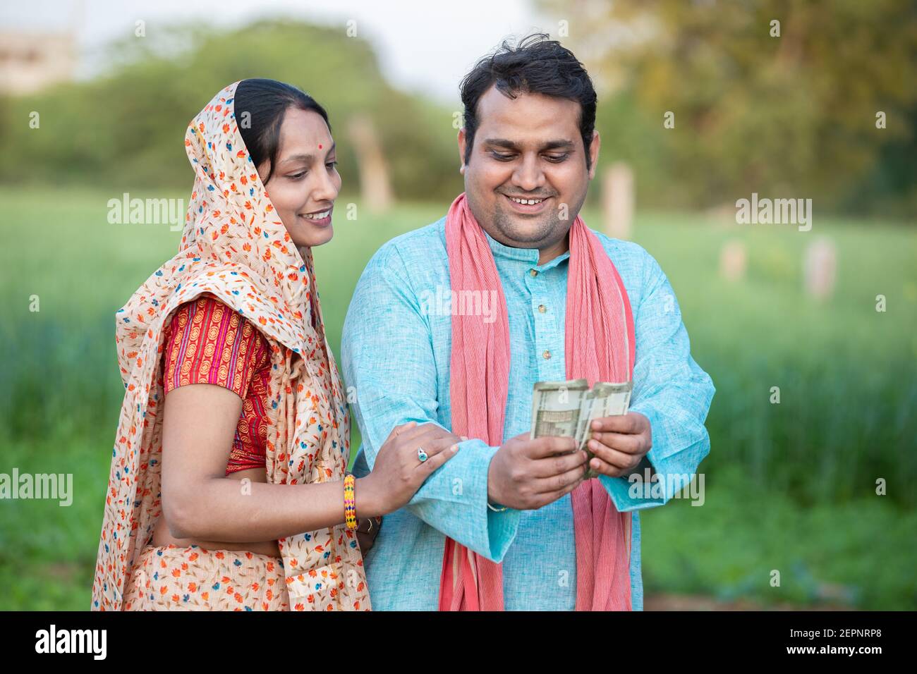 Happy Indian farmer couple counting rupees note at agriculture field ...
