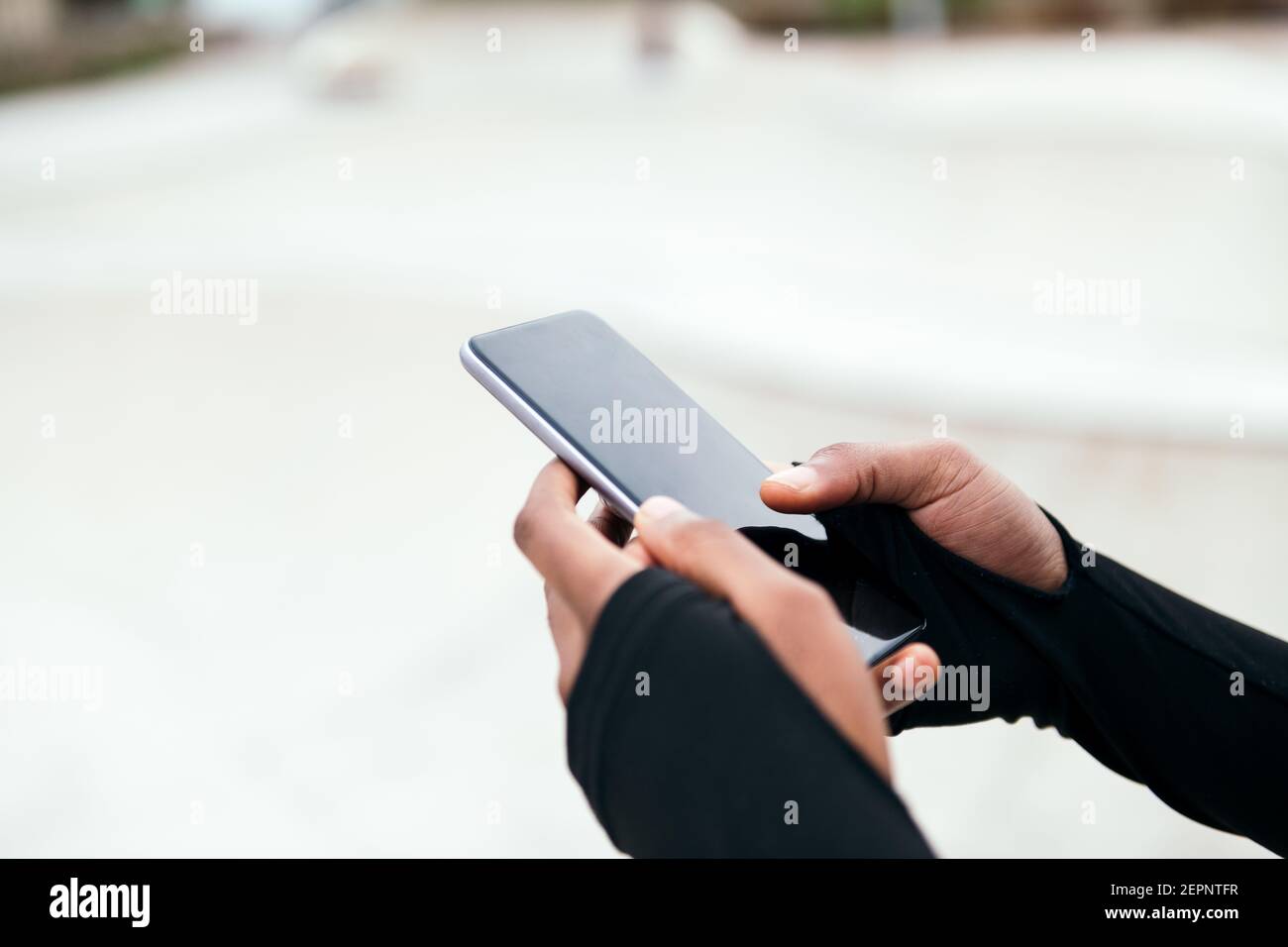 Crop anonymous ethnic female text messaging on mobile phone with black ...
