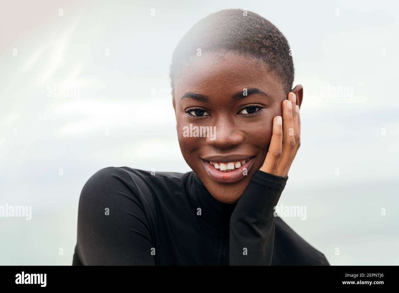 Young contemplative ethnic female with short hair touching face in ...