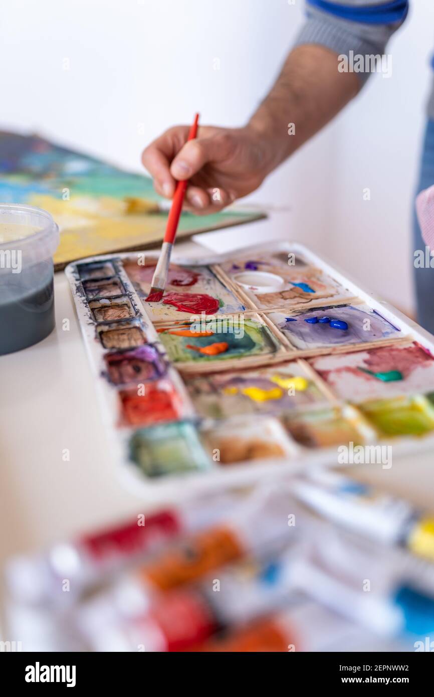 Crop anonymous male painter mixing paints with brush using watercolor ...