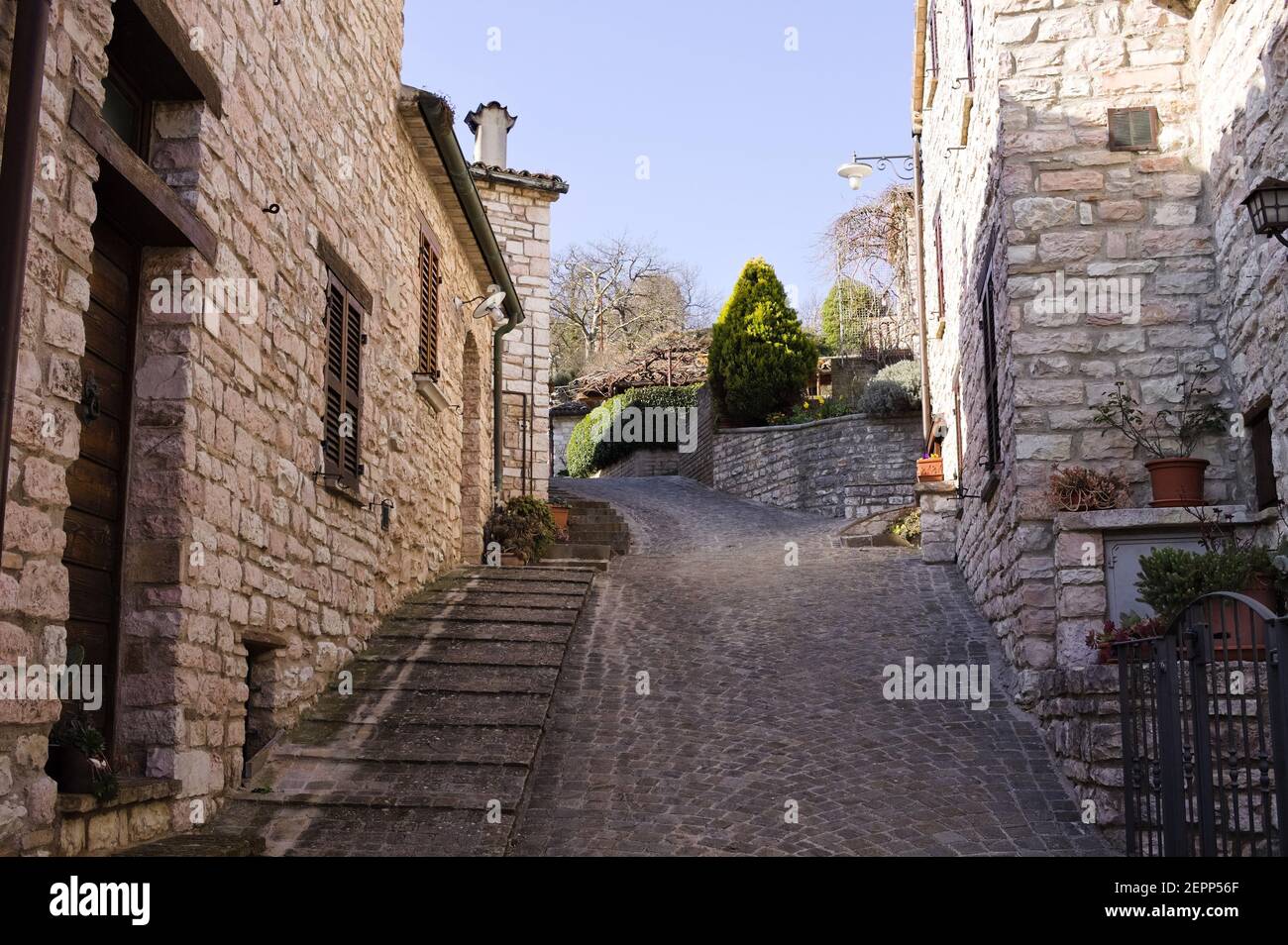 A staircase in a medieval Italian village with brick houses and floral ...