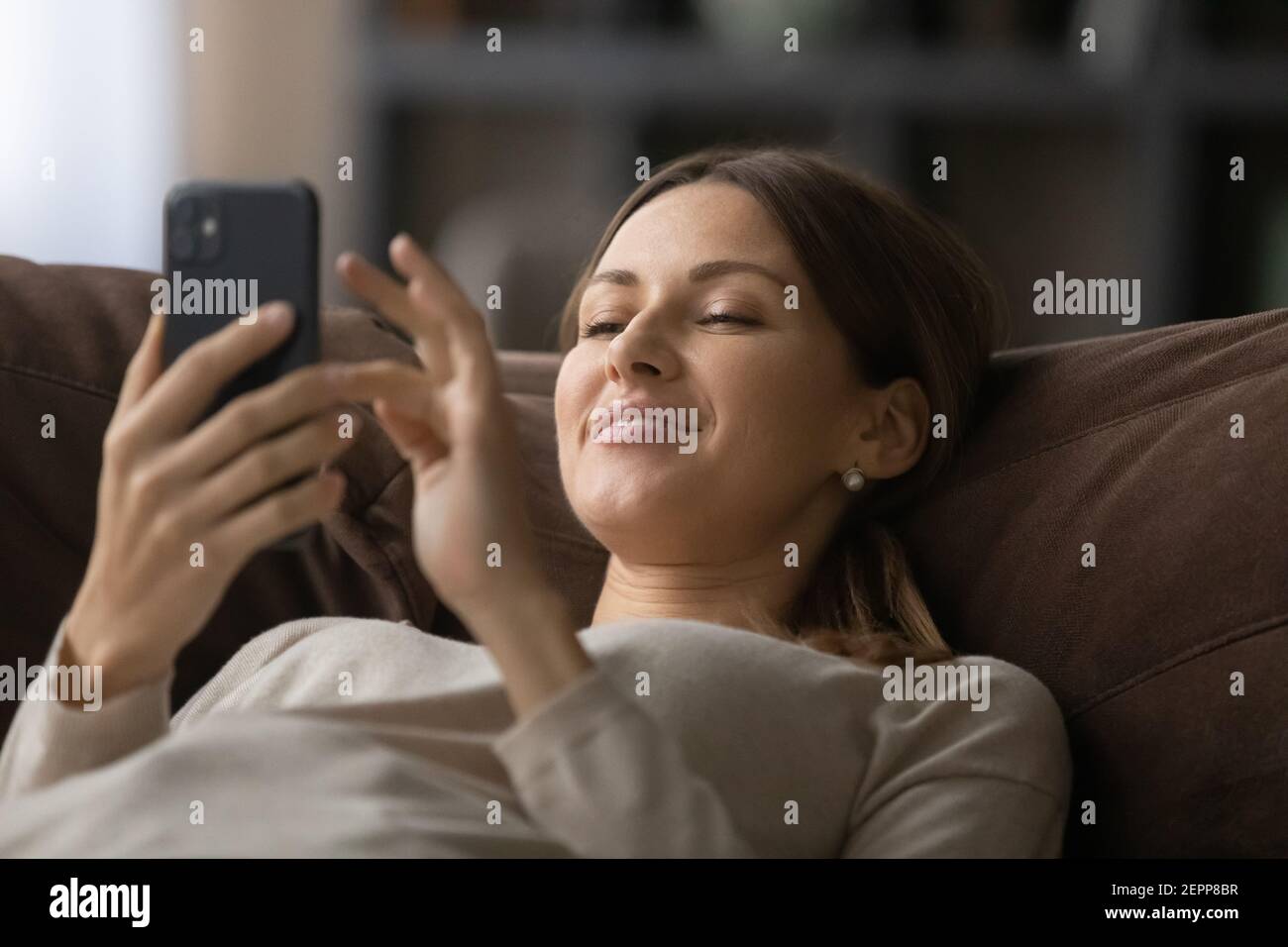 Happy Caucasian woman relax on sofa texting on cell Stock Photo - Alamy