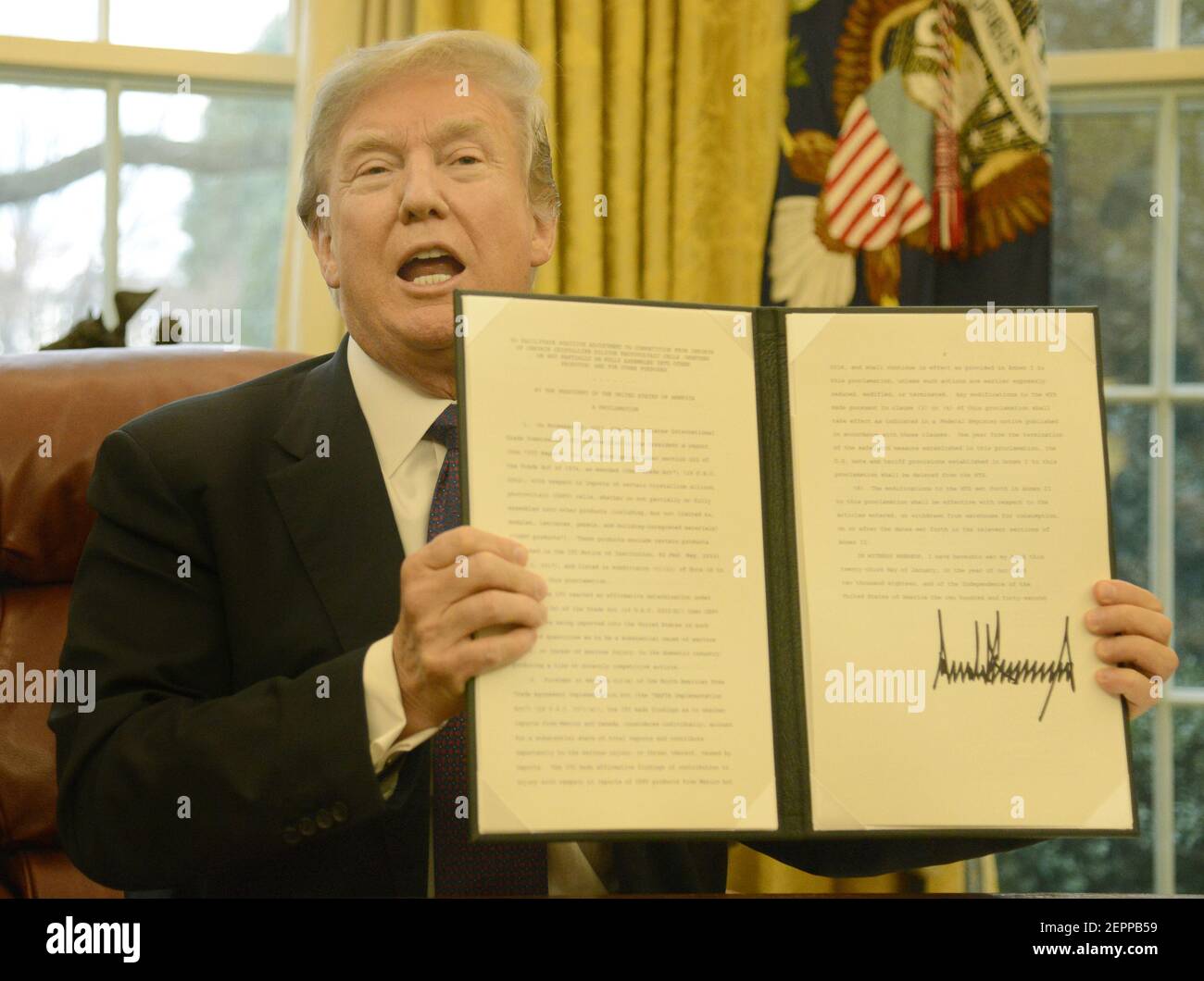 President Donald Trump holds up a Section 201 action after signing it ...