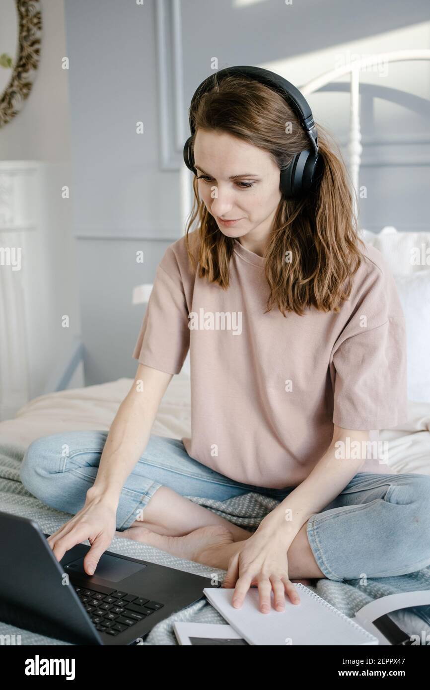 Distance learning online education and work.Happy woman in casual with the headphones working on ...