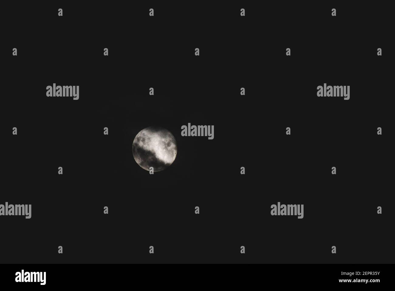 full moon with dark clouds in front of it creating a moody atmosphere ...