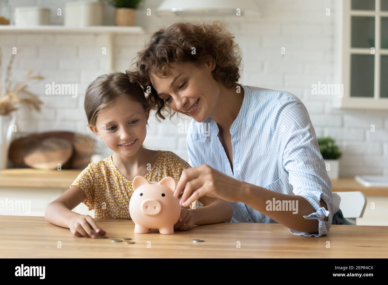 Friendly mom and daughter kid thrift coins in piggybank Stock Photo - Alamy