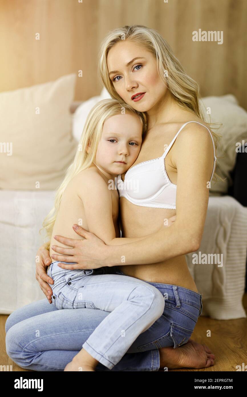 Happy mom and little daughter cuddle while dressing in sunny room ...