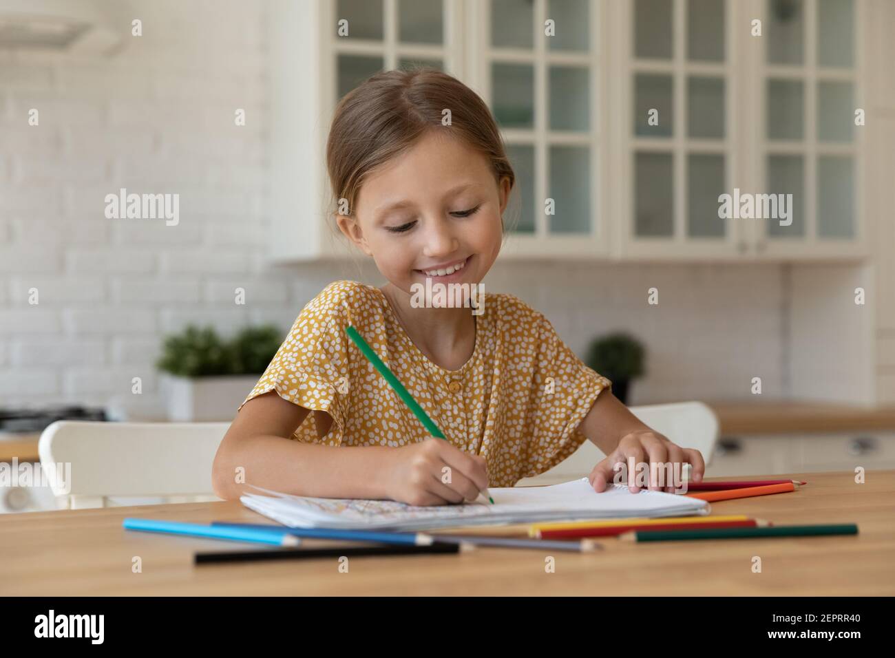 Inspired little girl sit at kitchen table drawing colorful picture ...