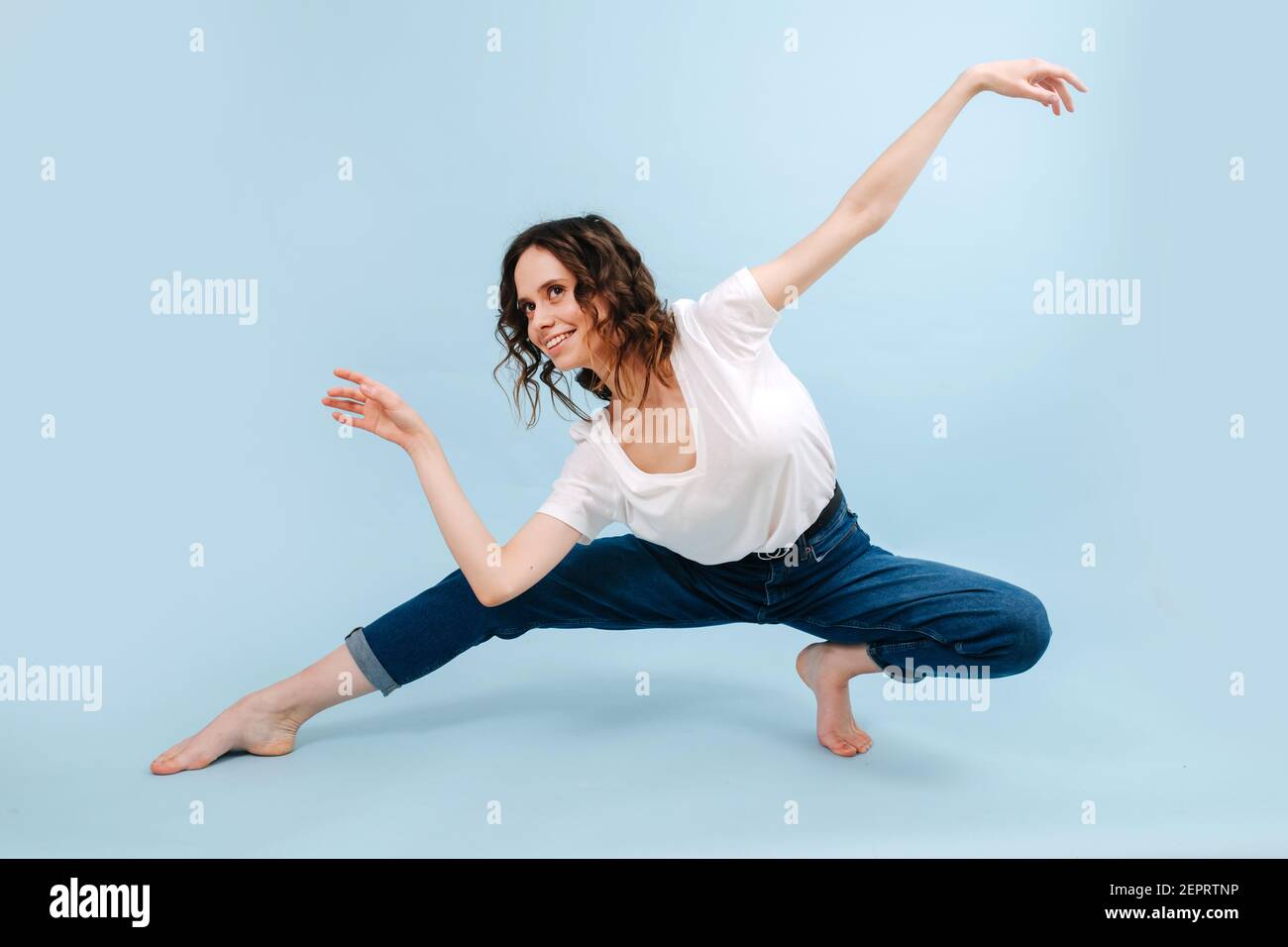 Playful contemporary dancer poses in front of blue studio background ...