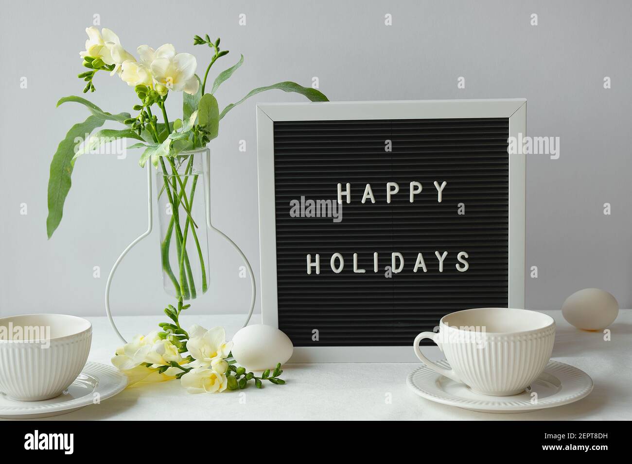 Text Happy Holidays on letter board with spring freesia flowers and tea ...