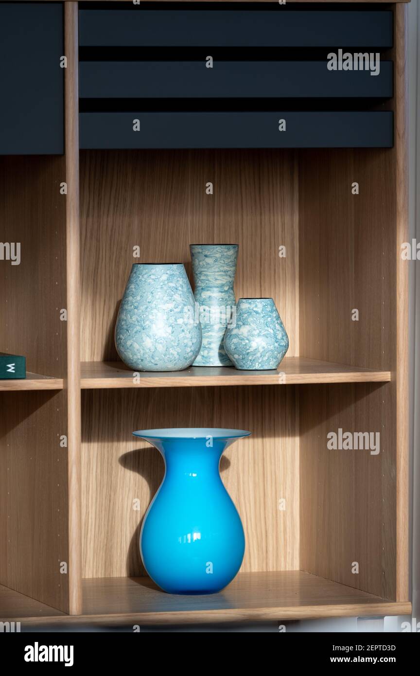 Different shaped blue vases in wooden sideboard shelf in natural light ...