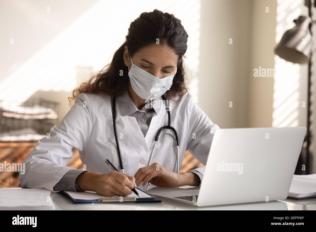 Close up serious female doctor wearing face mask taking notes Stock ...
