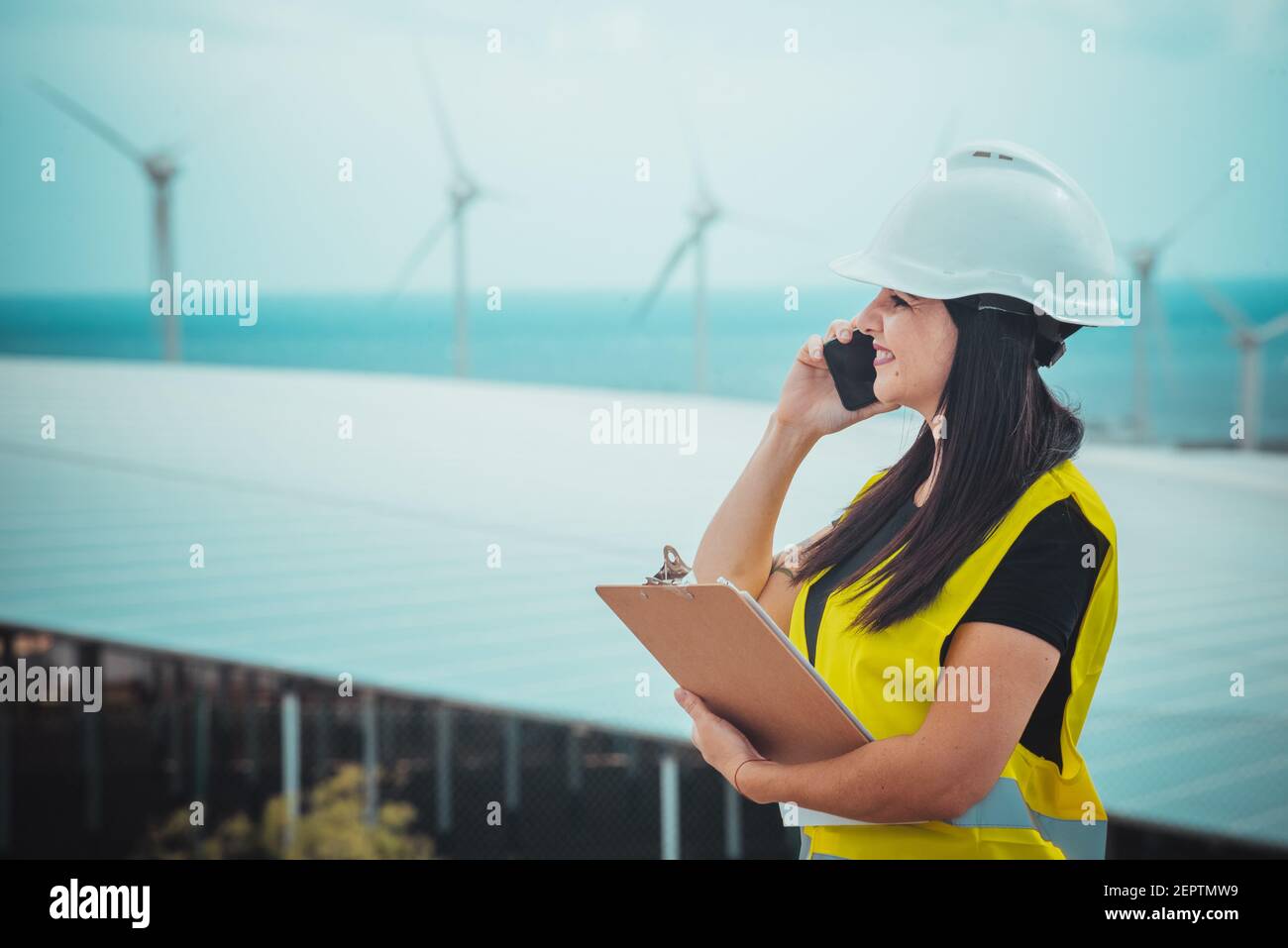 adult female engineer supervises solar panels and windmills in a ...